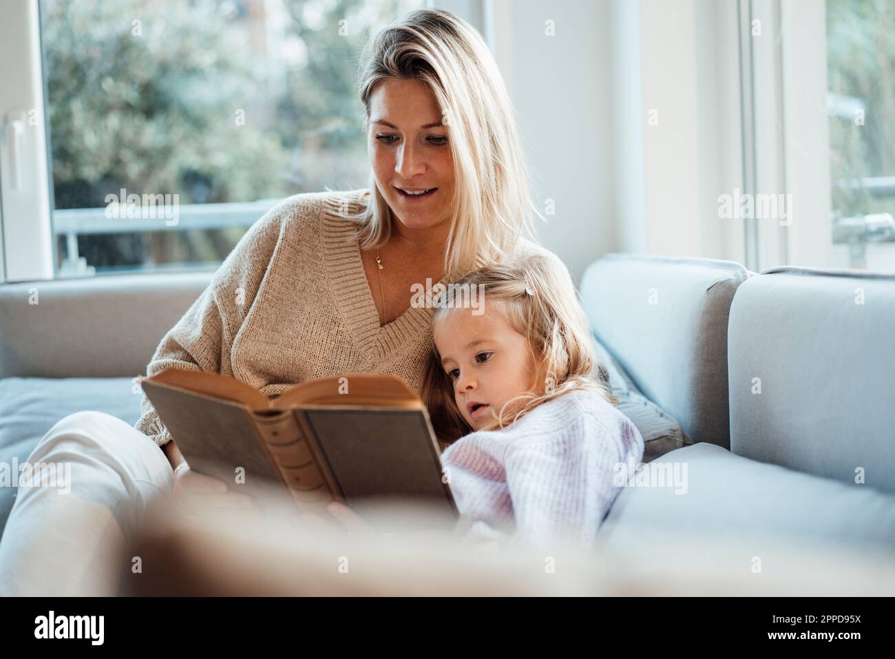 Mother reading book to daughter at home Stock Photo - Alamy