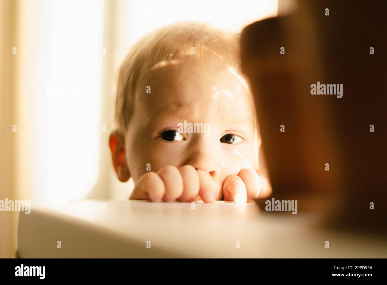 Sad boy hiding near window at home Stock Photo - Alamy
