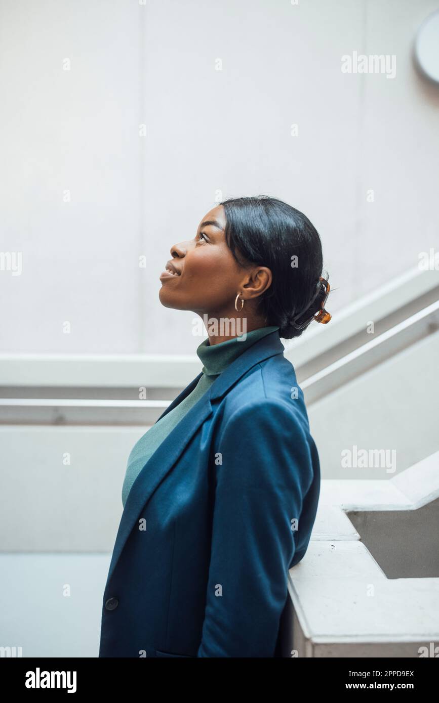 Smiling businesswoman looking up leaning on railing Stock Photo - Alamy
