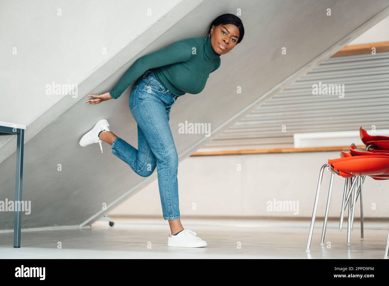 Young woman standing on one leg under staircase Stock Photo - Alamy