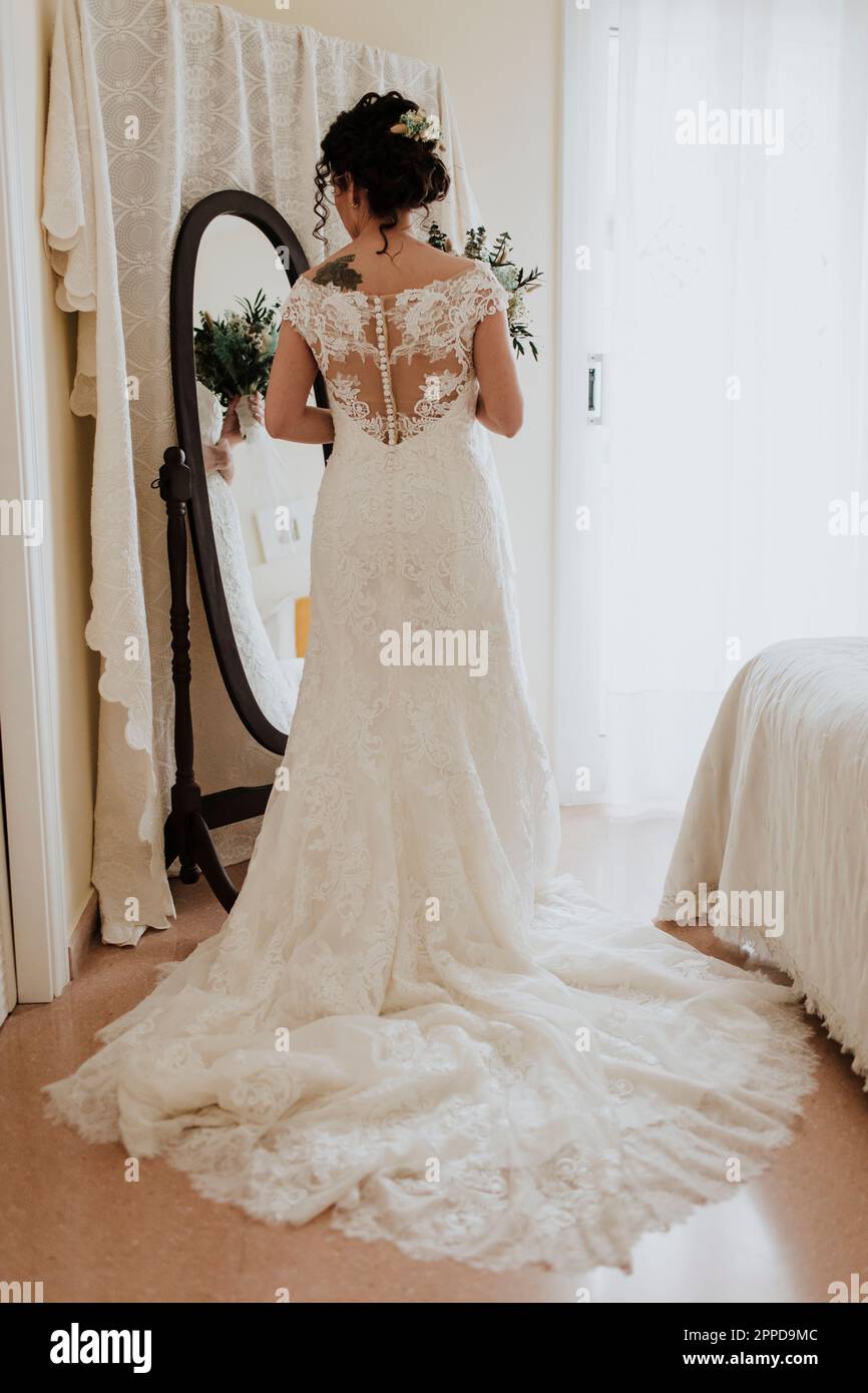 Bride in wedding dress looking in mirror Stock Photo - Alamy