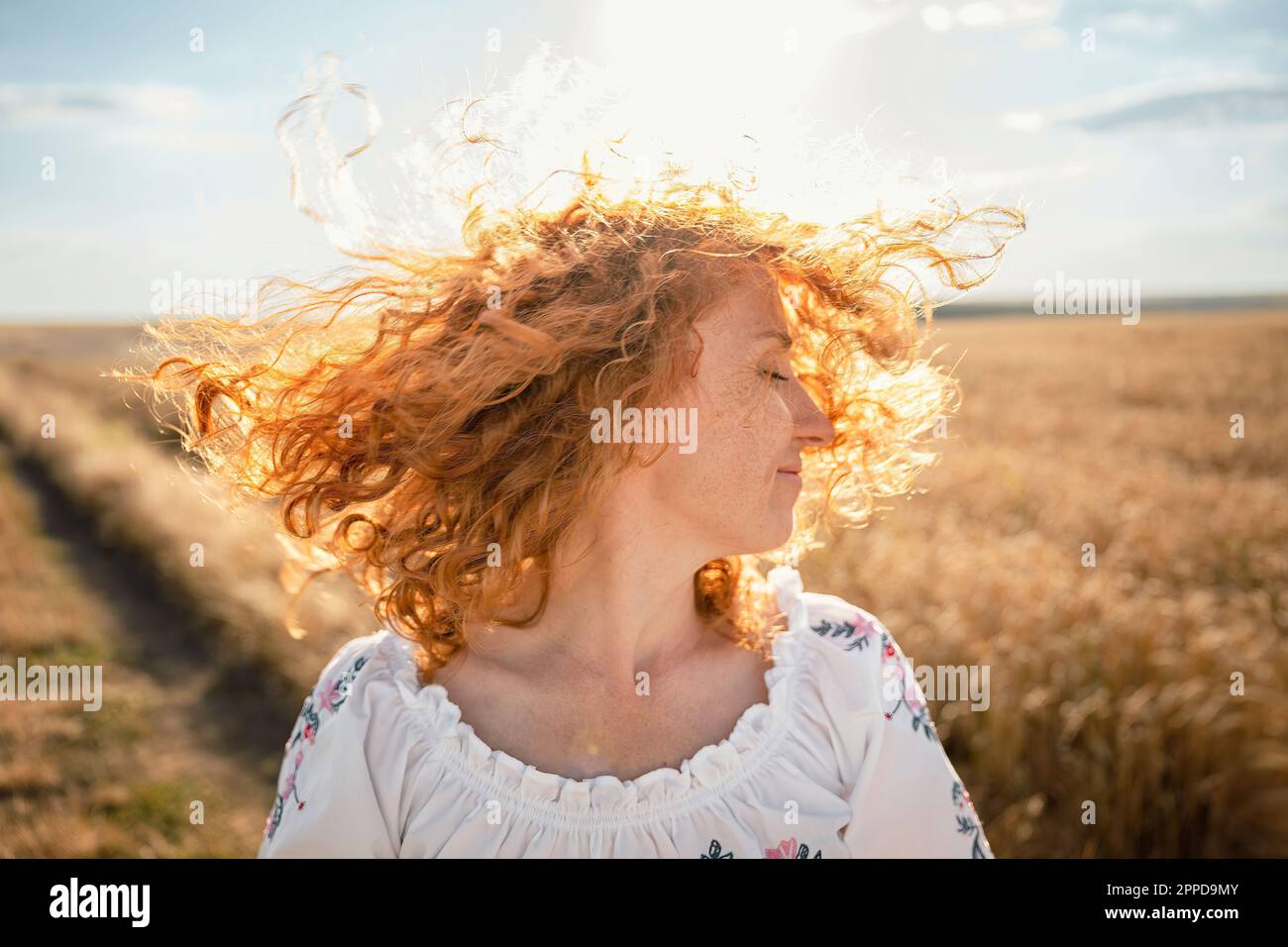 Happy redhead woman tossing hair in field Stock Photo - Alamy