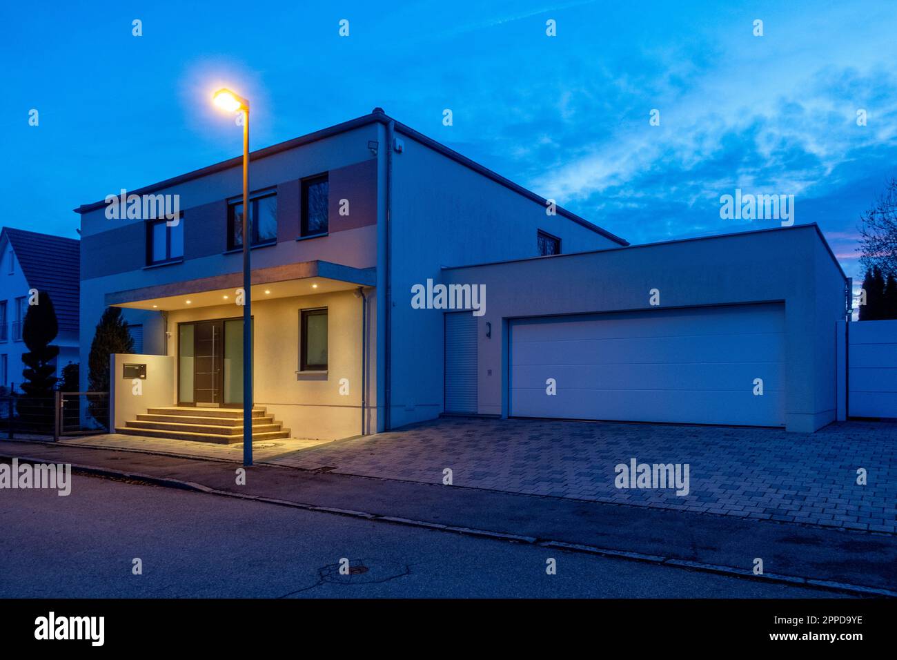 Germany, Bavaria, Street light glowing in front of modern suburban ...