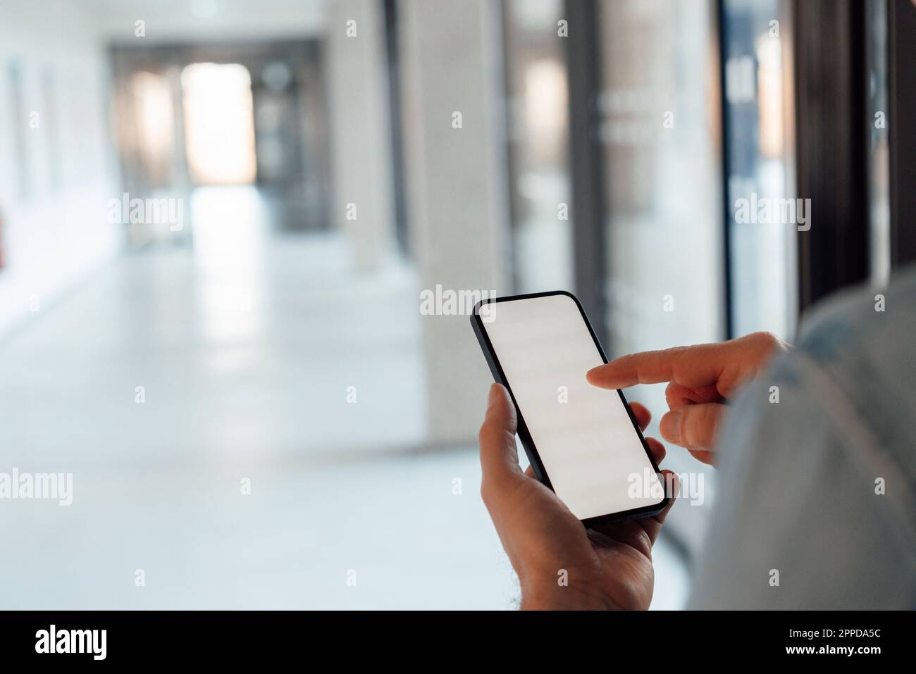 Businessman touching screen of smart phone at corridor Stock Photo - Alamy