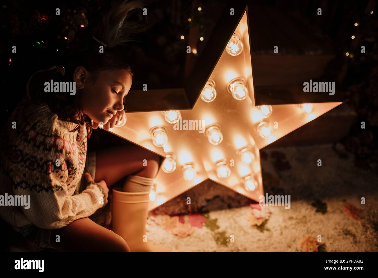 Girl with eyes closed leaning head on star shape light Stock Photo - Alamy