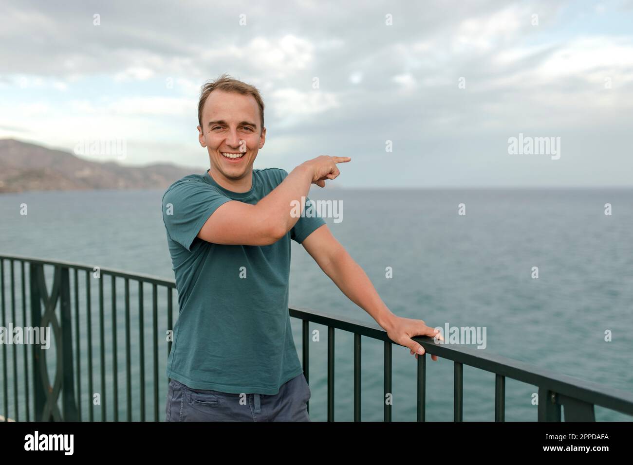 Happy man pointing towards sea Stock Photo - Alamy