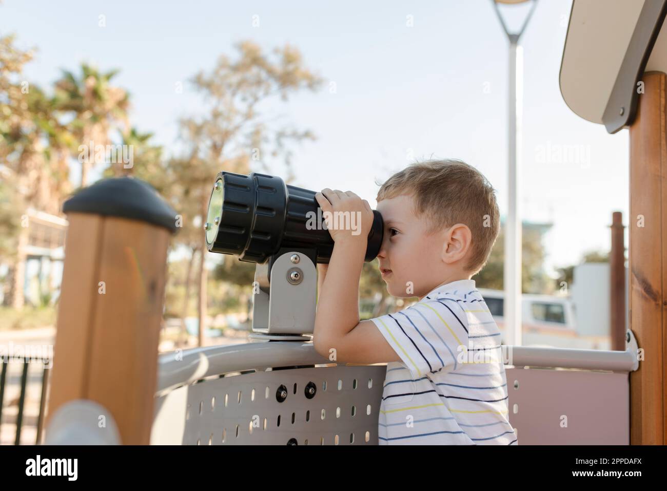 Boy looking through telescope at playground Stock Photo - Alamy