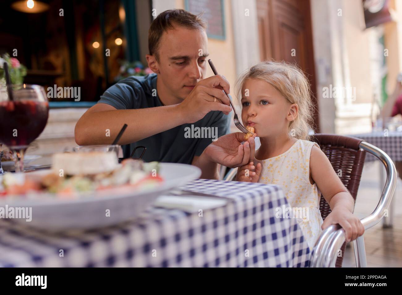 Father feeding shrimp to daughter in restaurant Stock Photo - Alamy