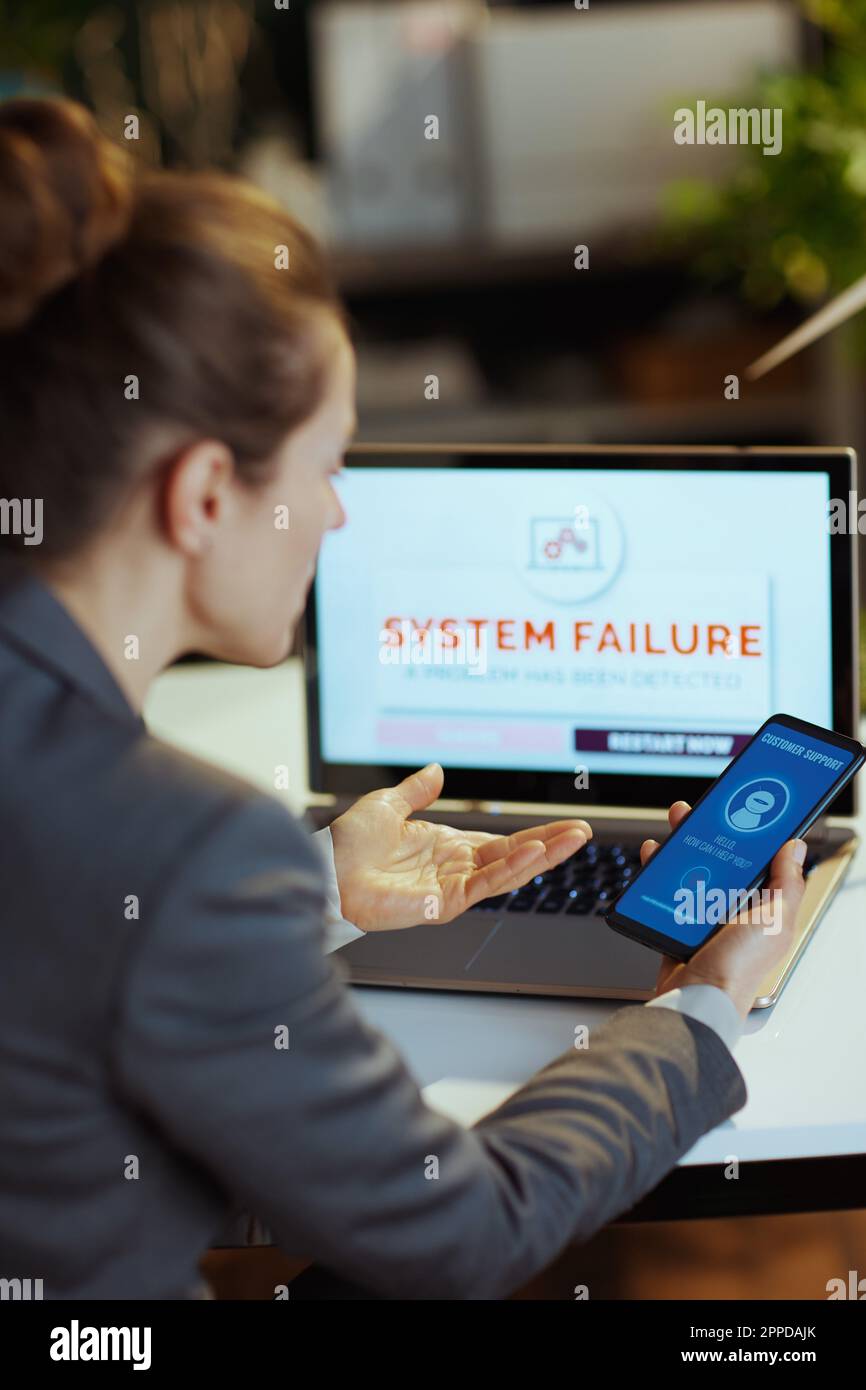 Seen from behind modern woman with laptop and smartphone experiencing ...