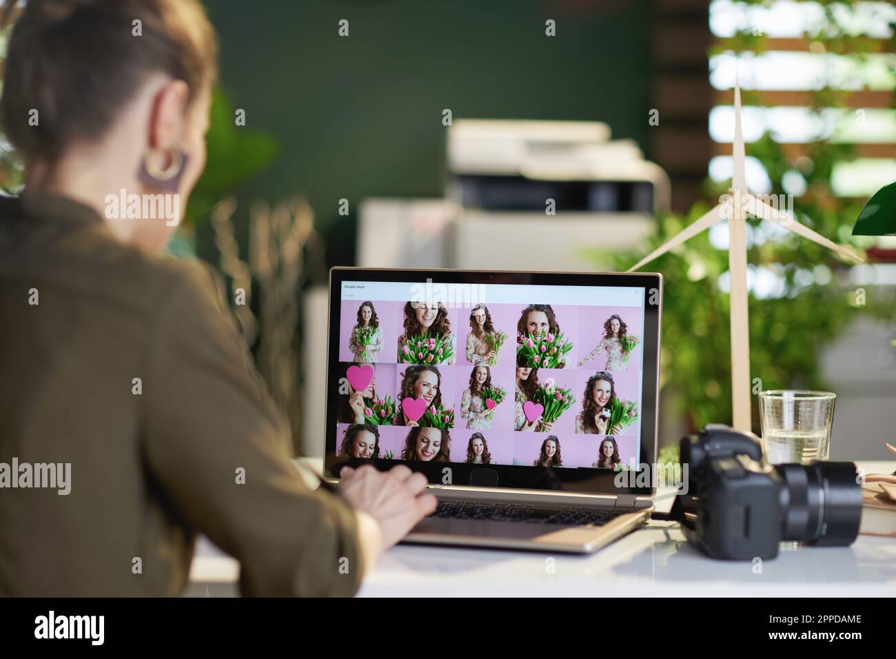 Seen from behind female photographer with laptop and photo camera ...