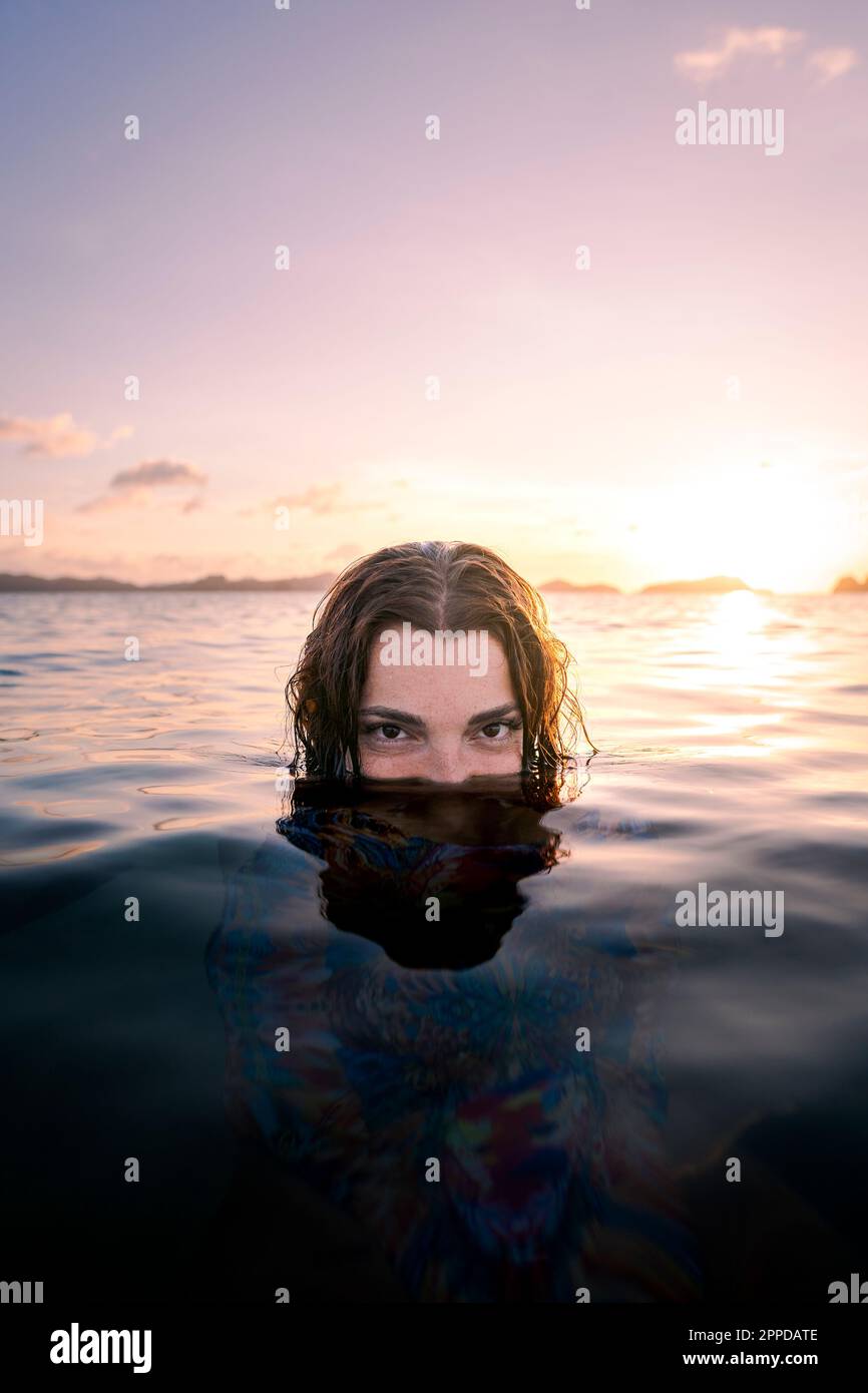 Woman hiding face in water at beach on sunset Stock Photo - Alamy