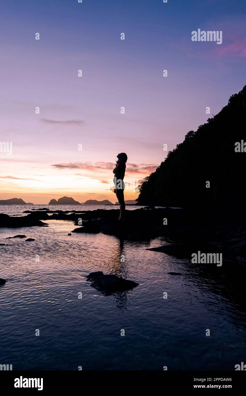 Silhouette of woman standing on rock at beach Stock Photo - Alamy