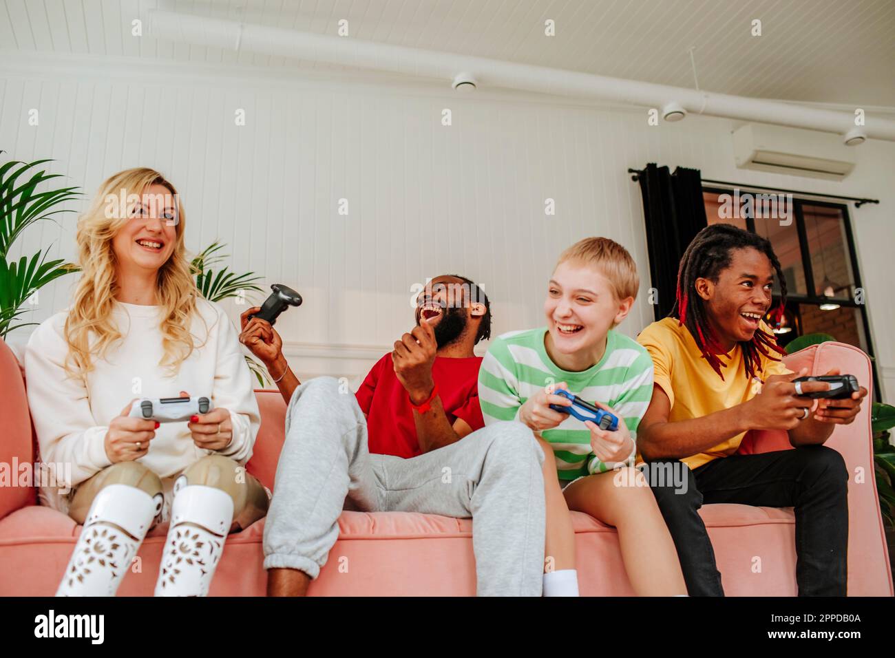 Excited young man playing video game with friends on sofa Stock Photo ...