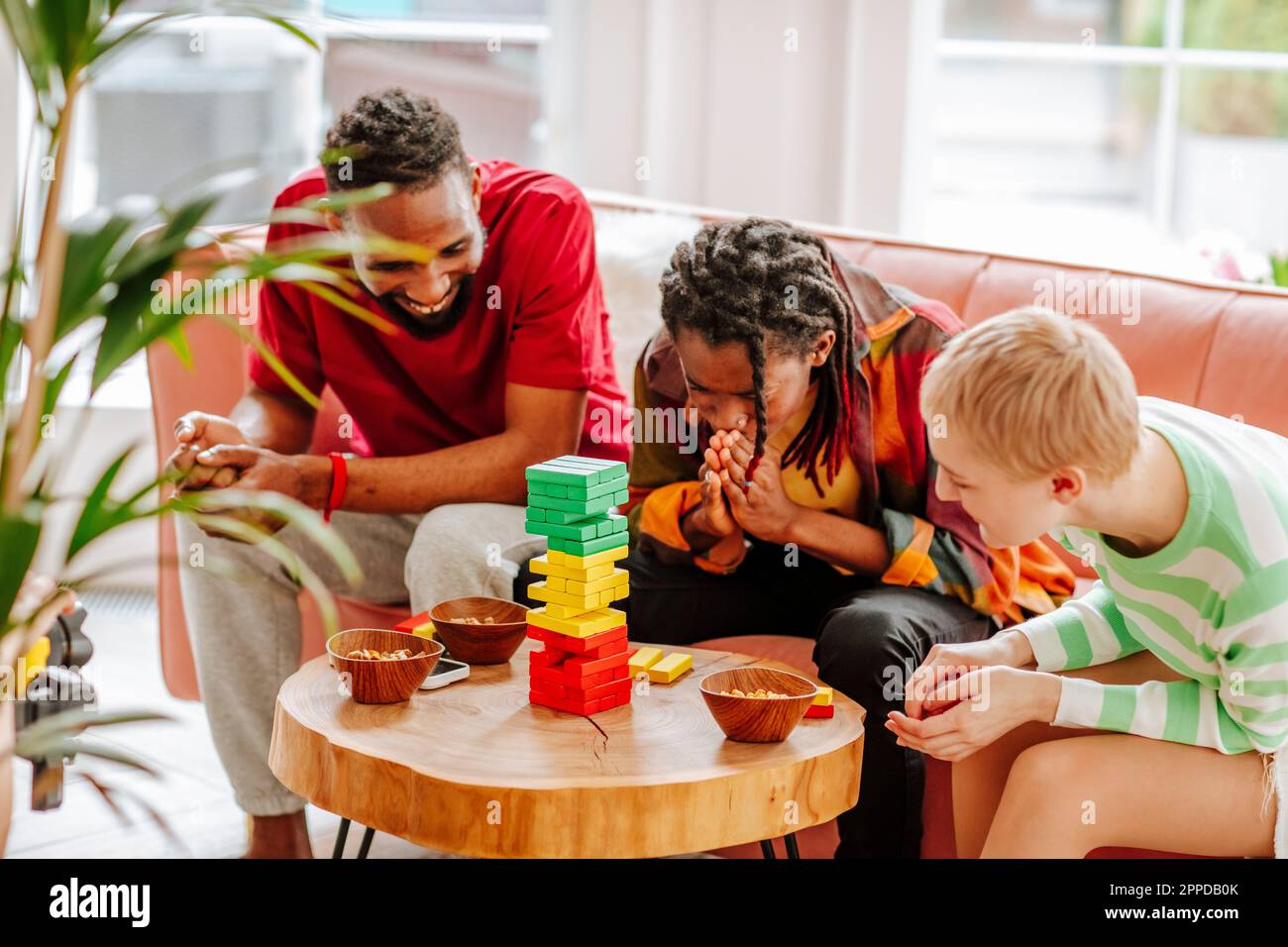 Young multiracial friends playing block removal game in living room ...