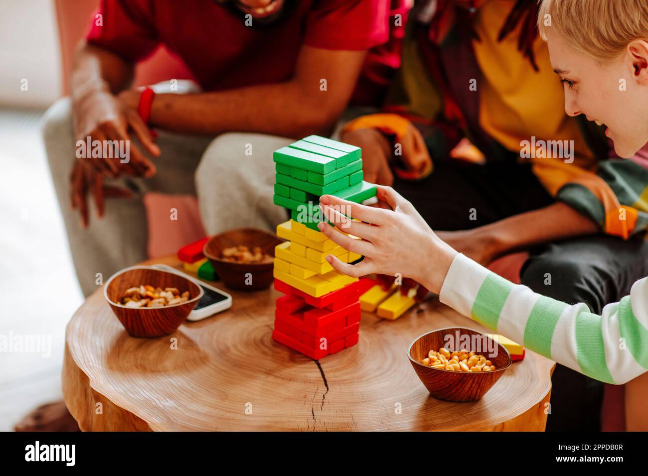 Happy friends playing block removal game on table at home Stock Photo ...