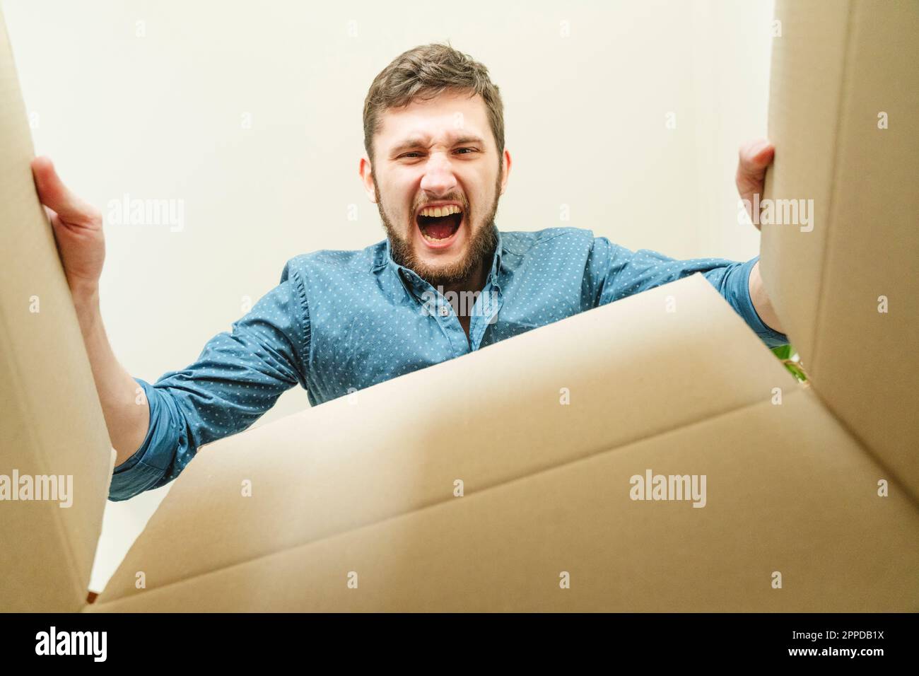 Young man screaming and looking inside cardboard box Stock Photo - Alamy
