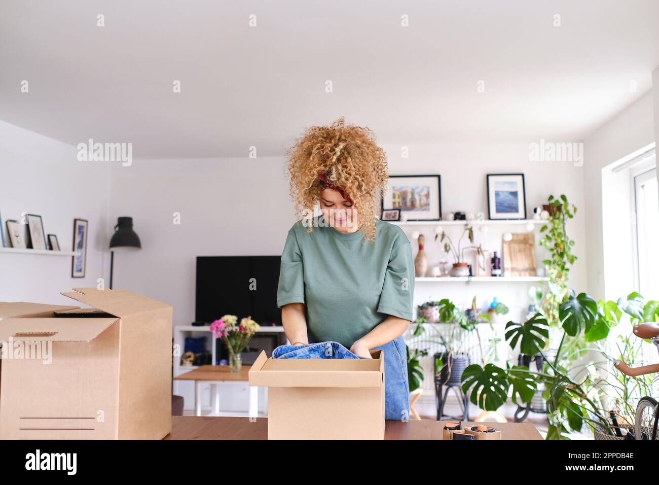 Smiling young woman packing order at home Stock Photo - Alamy