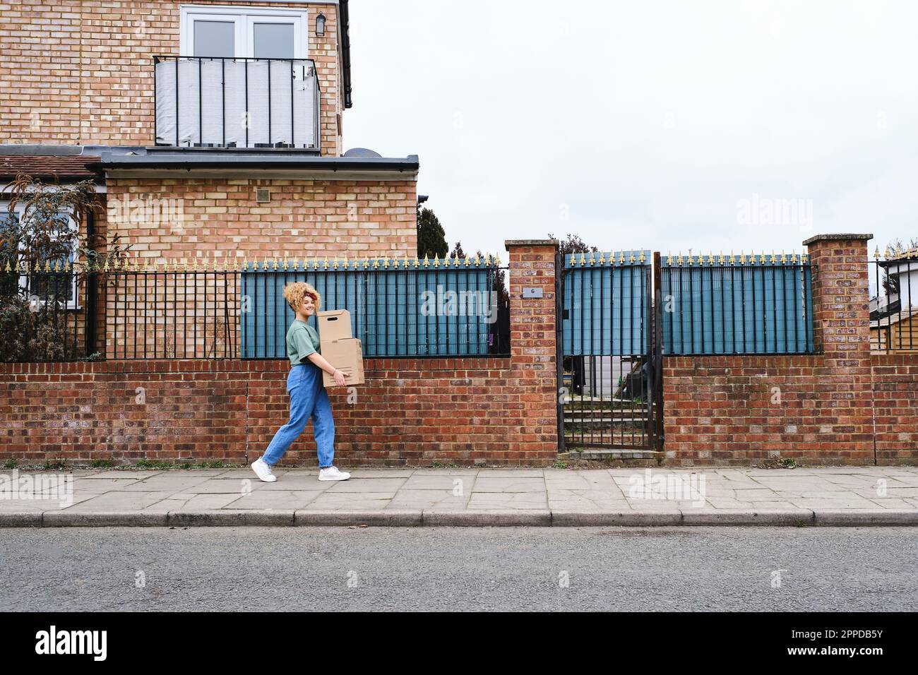 Young woman walking with cardboard boxes on footpath Stock Photo - Alamy