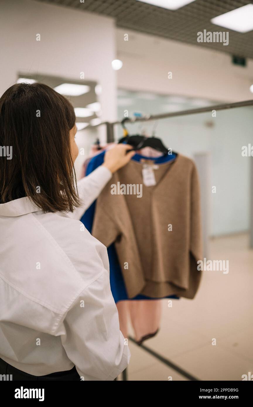 Woman hanging clothes on rack Stock Photo - Alamy