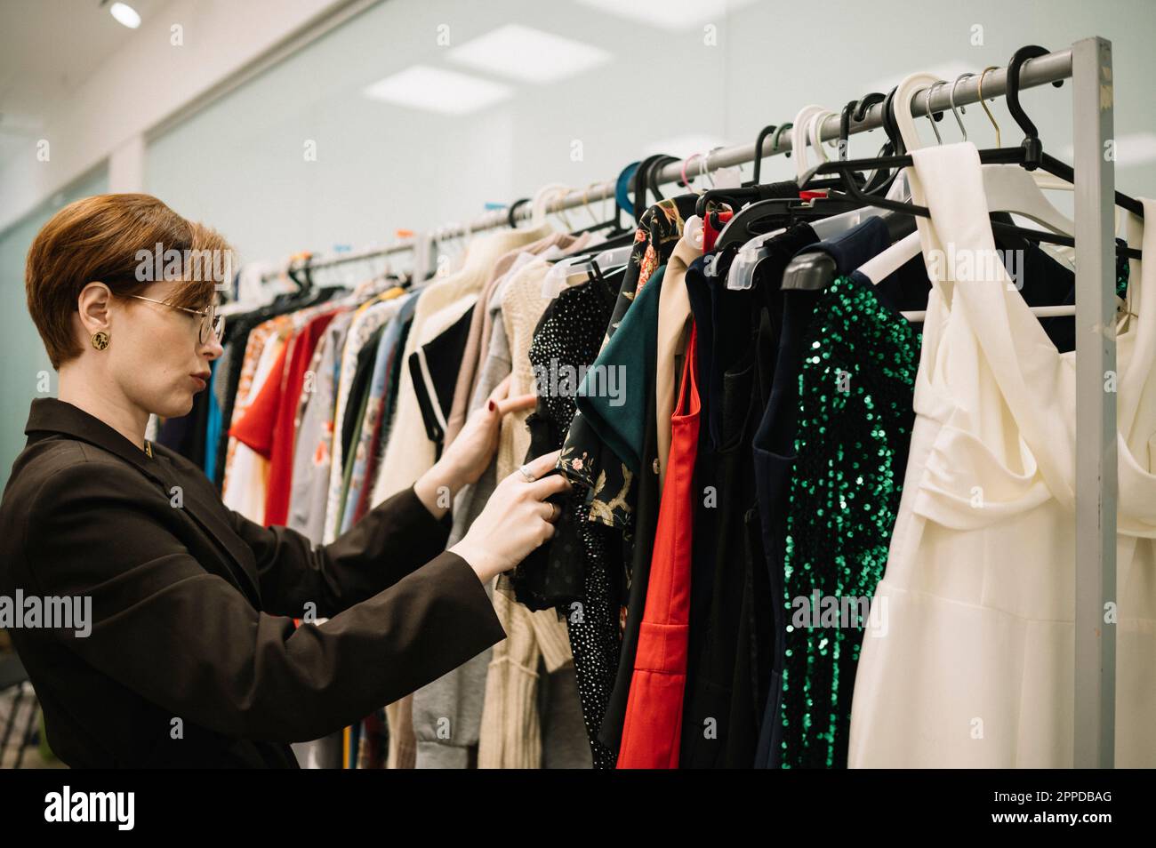 Store owner examining clothes in store Stock Photo - Alamy