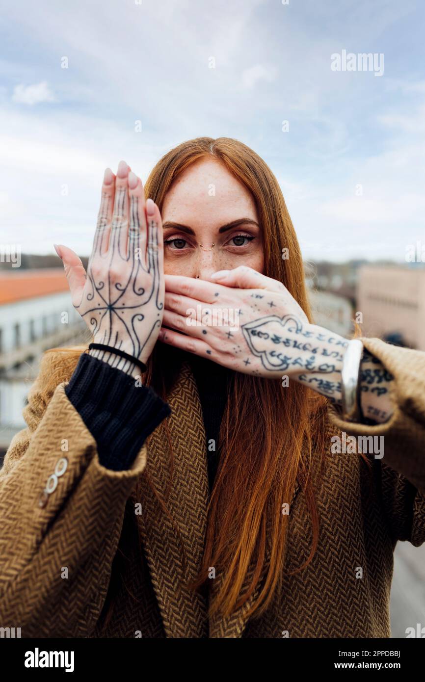 Woman with tattooed hand covering face Stock Photo - Alamy