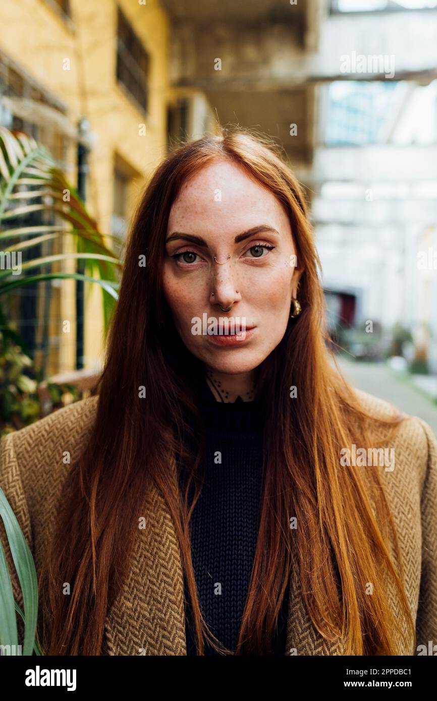 Redhead woman standing in front of building Stock Photo - Alamy