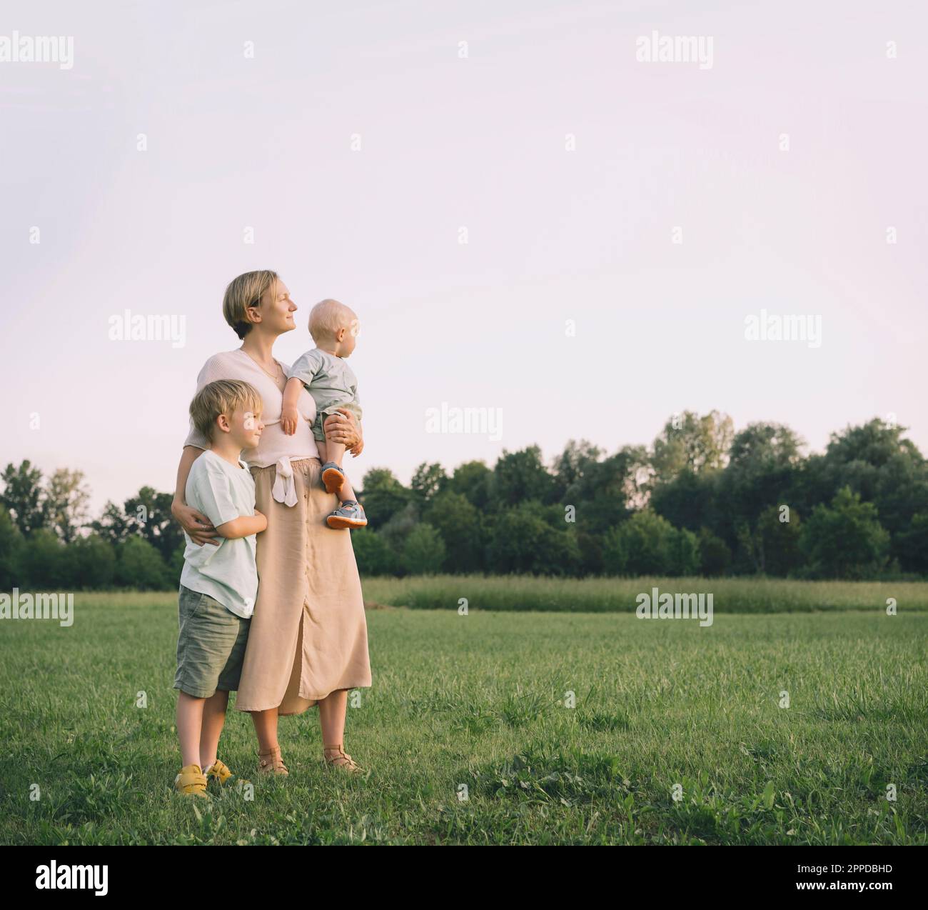 Loving mother with children standing in nature at sunset Stock Photo ...
