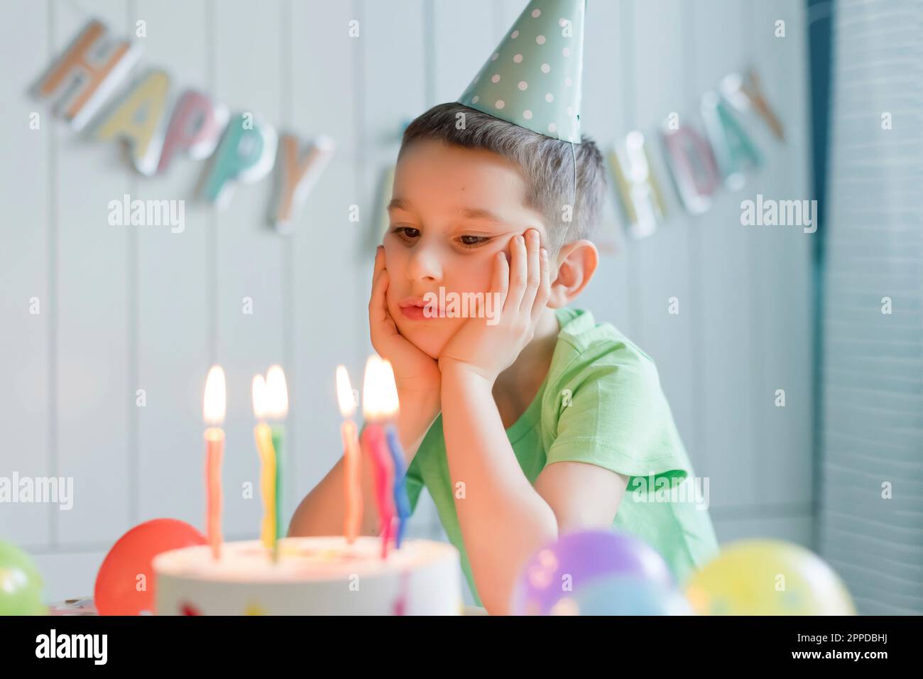 Sad elementary boy looking at birthday cake Stock Photo - Alamy