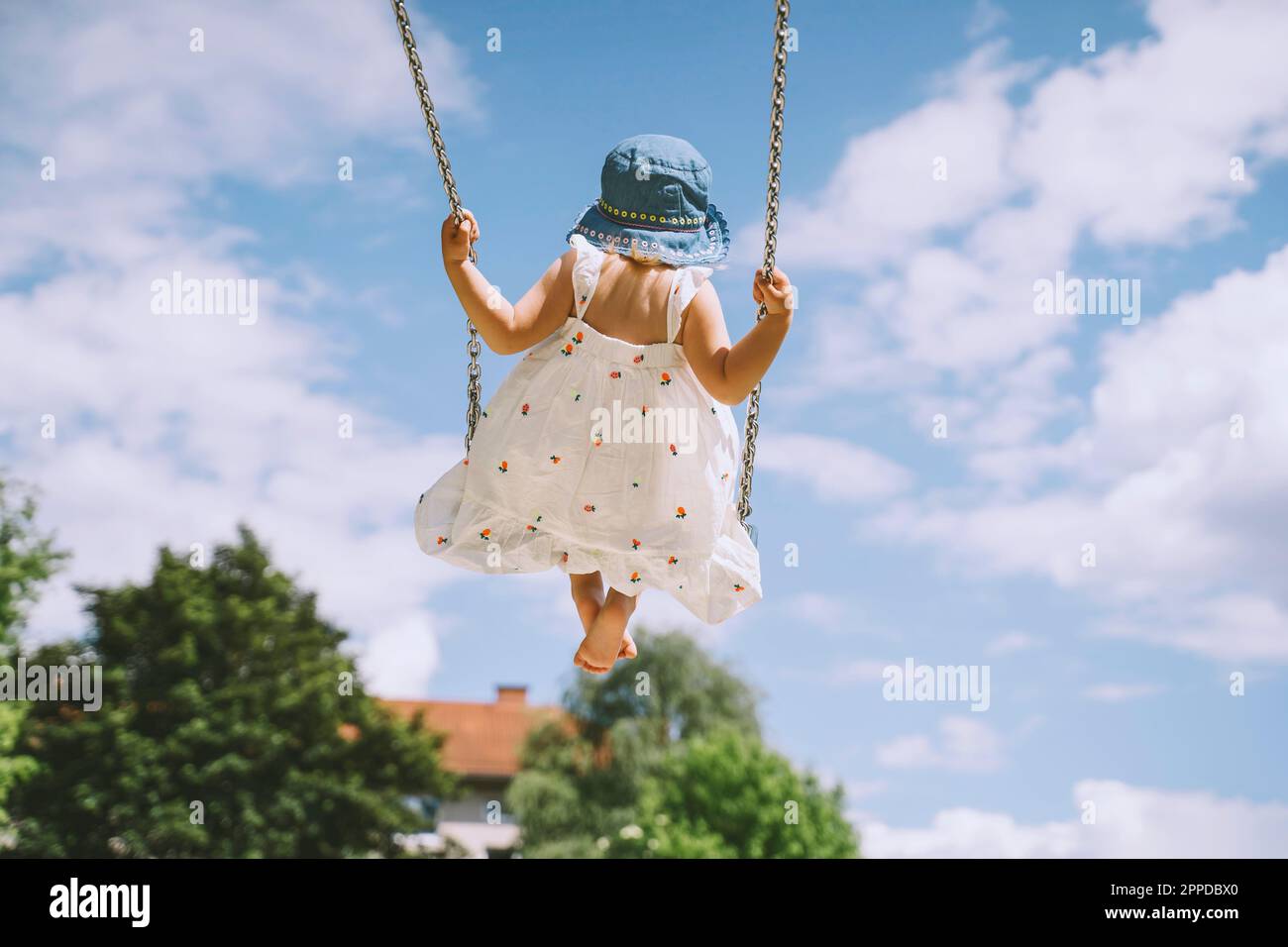 Girl swinging on swing in front of cloudy sky Stock Photo - Alamy