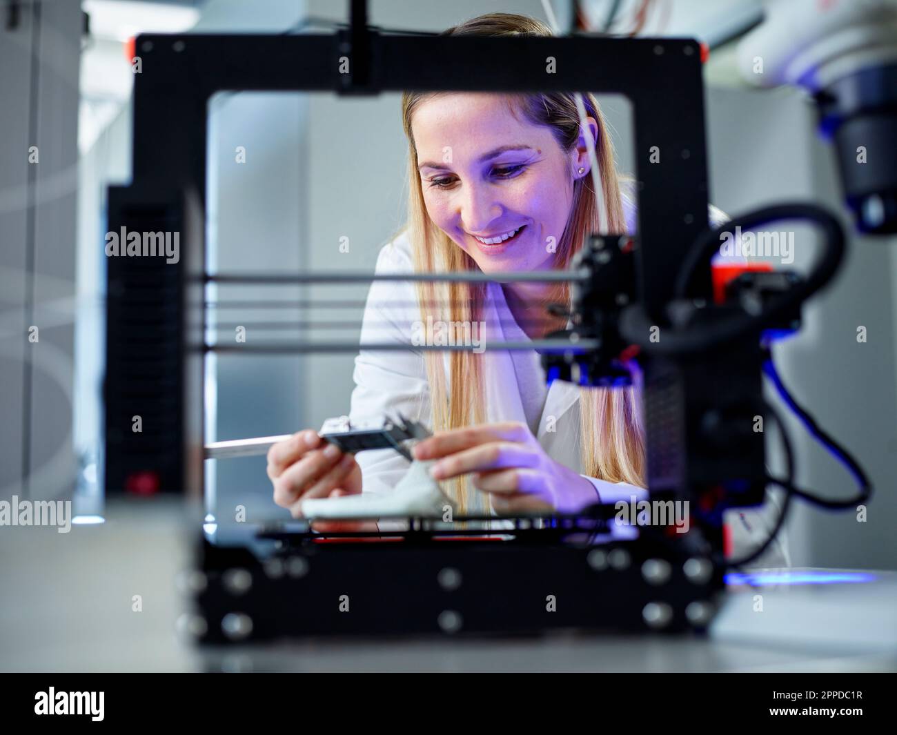 Smiling engineer holding vernier calliper operating 3D printing machine ...