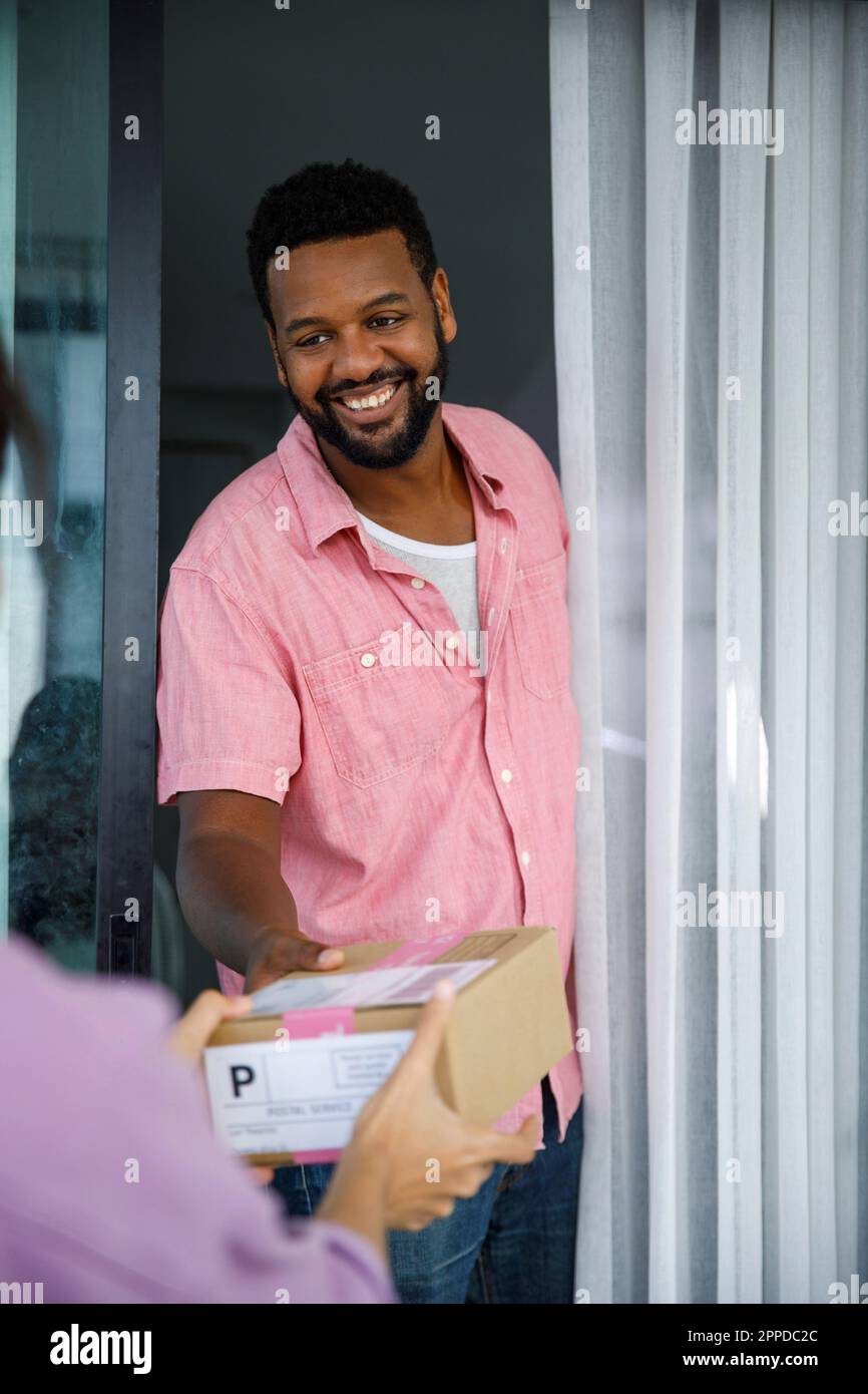 Happy man receiving parcel at doorway Stock Photo - Alamy