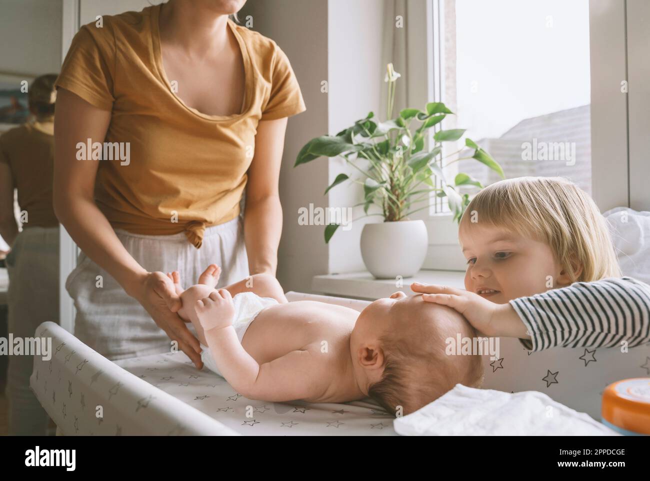 Girl helping mother taking care of baby boy at home Stock Photo - Alamy