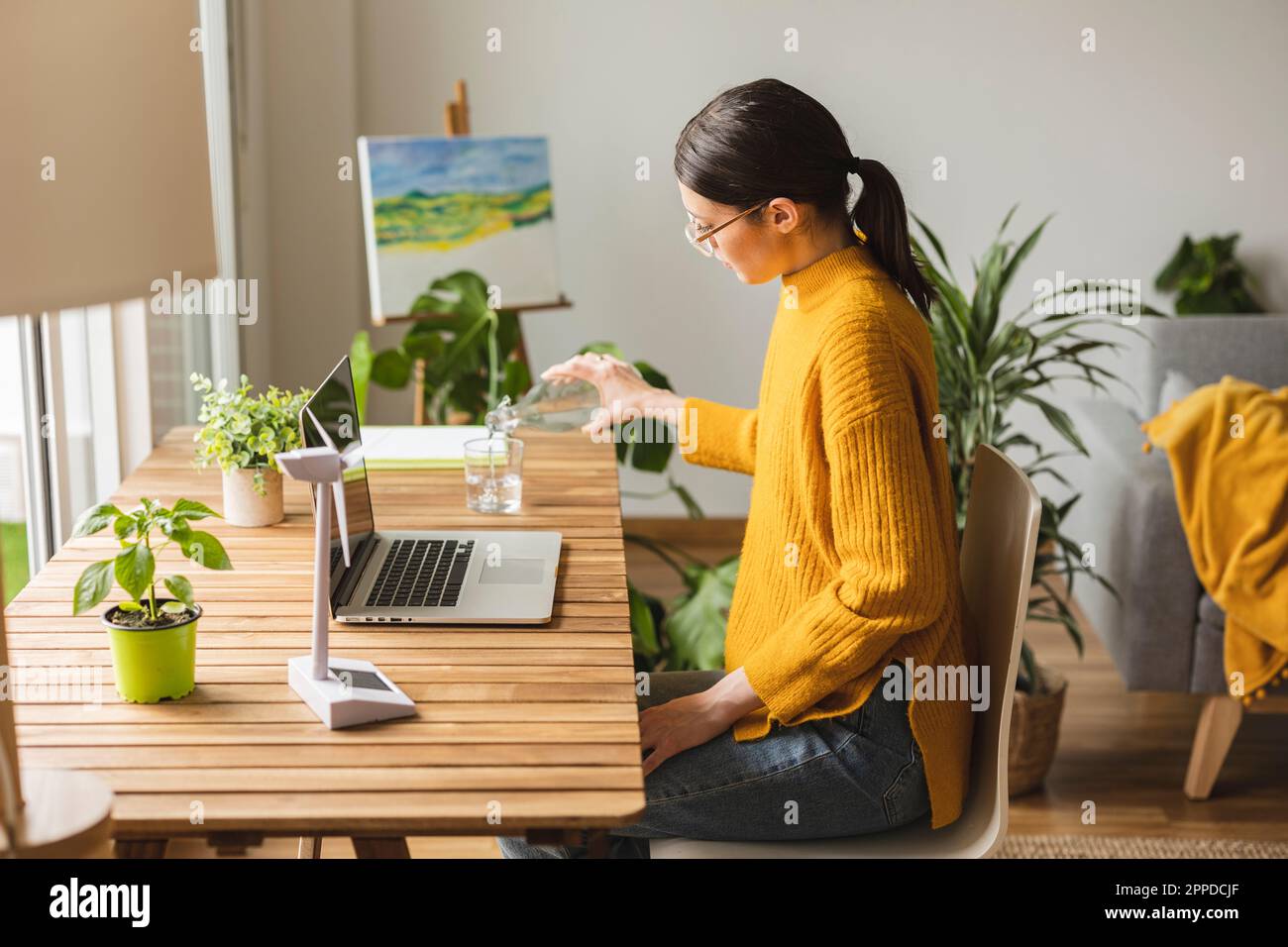 Young freelancer pouring water in glass at desk Stock Photo - Alamy