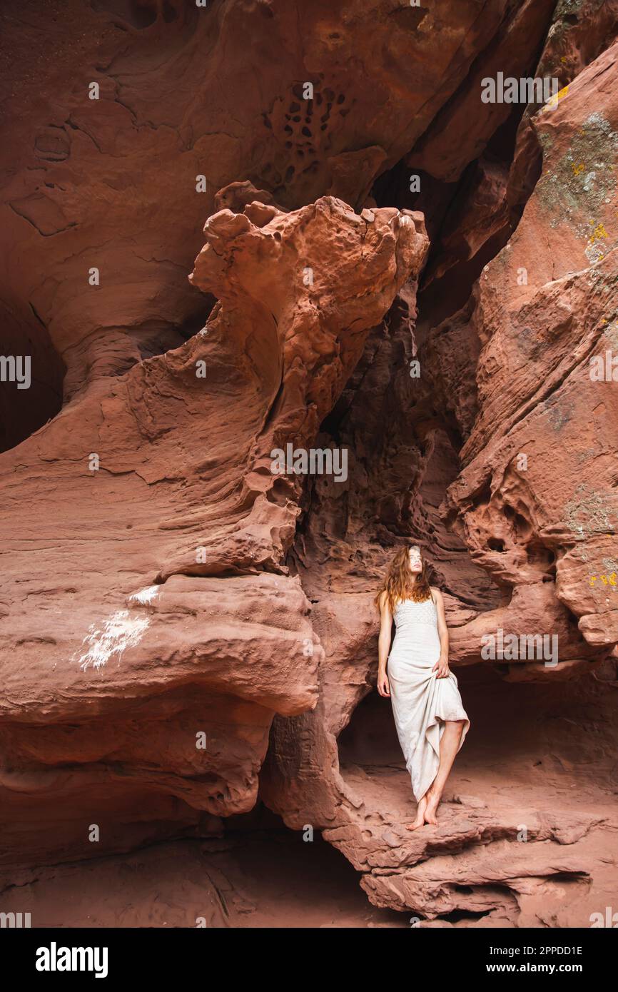 Young woman leaning on rock in red cave Stock Photo - Alamy