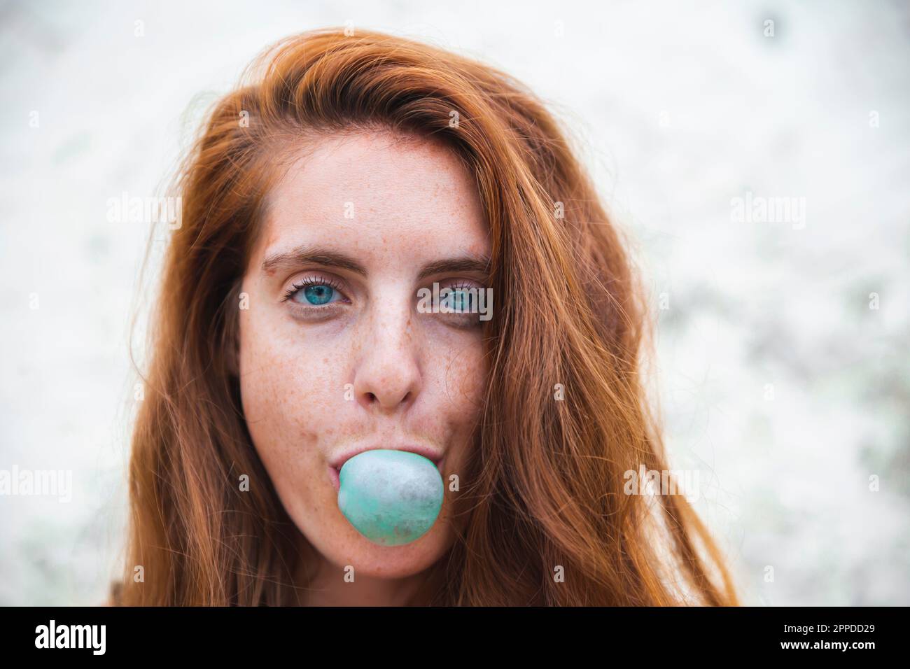 Redhead woman chewing bubble gum Stock Photo - Alamy
