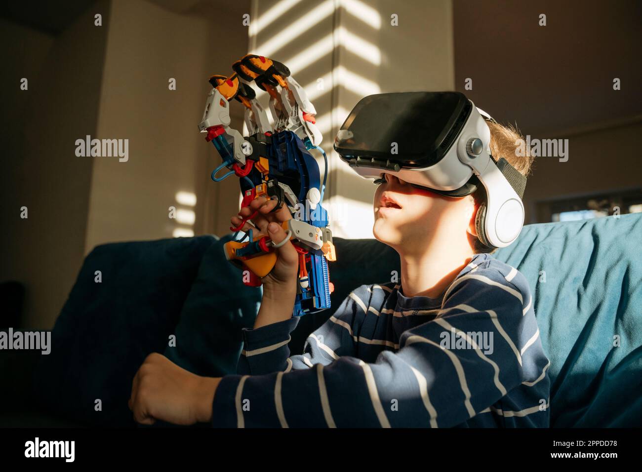 Boy wearing virtual reality simulator holding robotic arm at home Stock ...