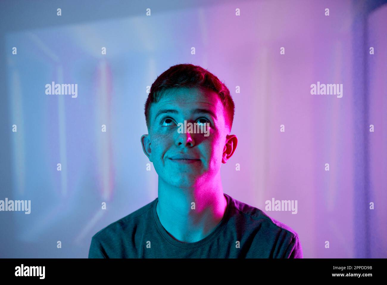 Young man with illuminated light on face in front of wall Stock Photo ...