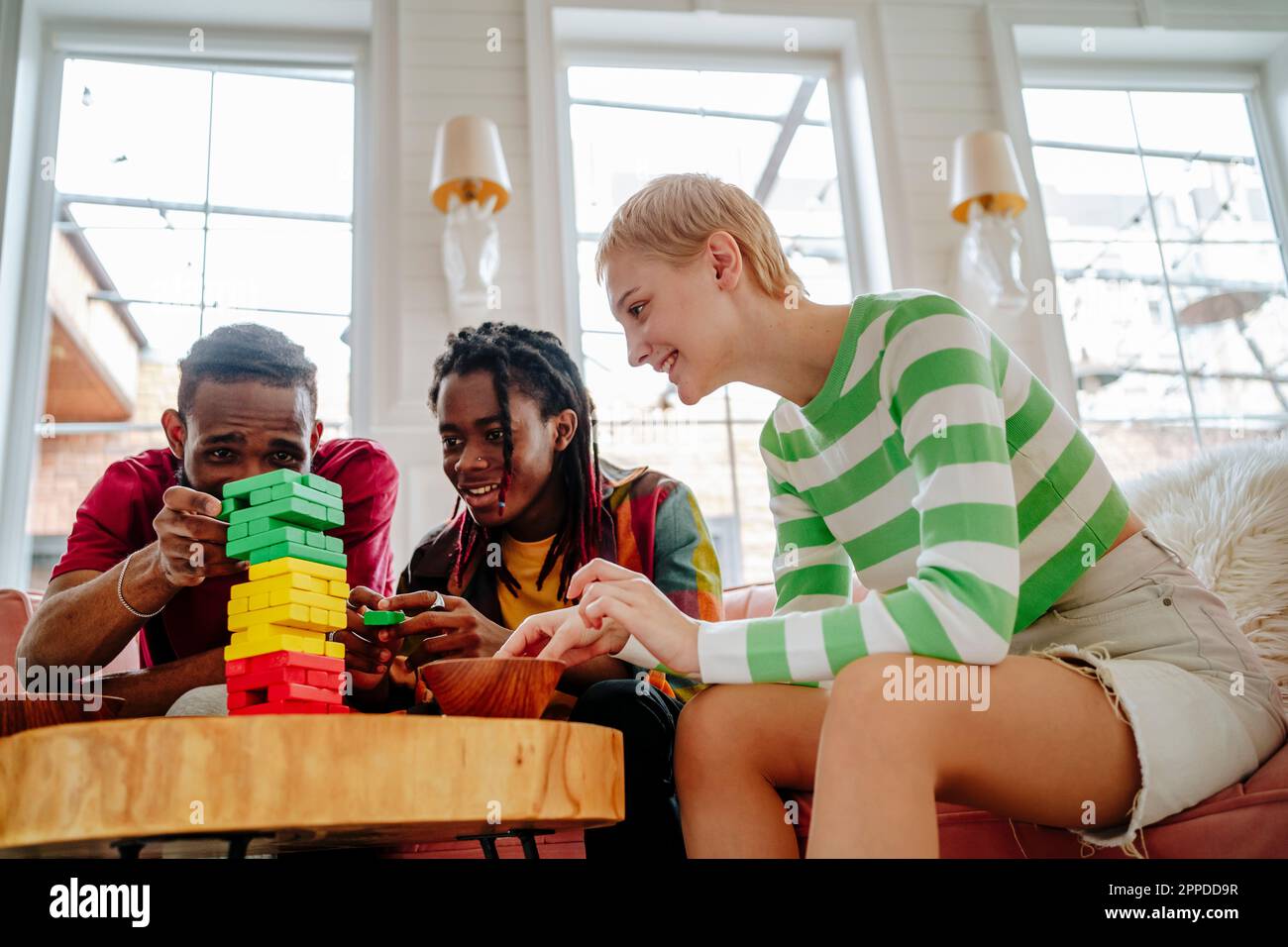 Happy young woman playing block removal game with friends Stock Photo ...