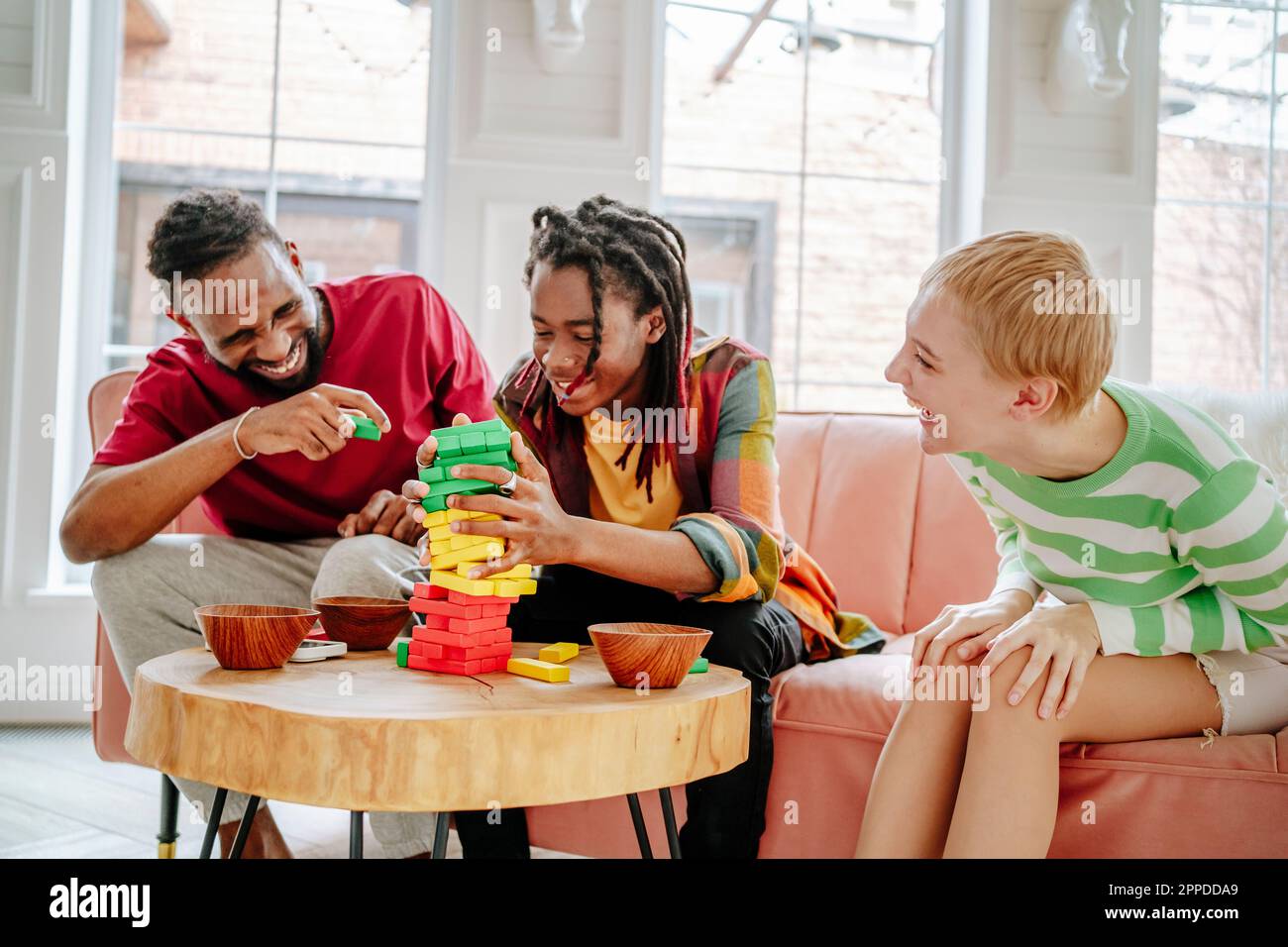 Cheerful man with friends playing block removal game at home Stock ...