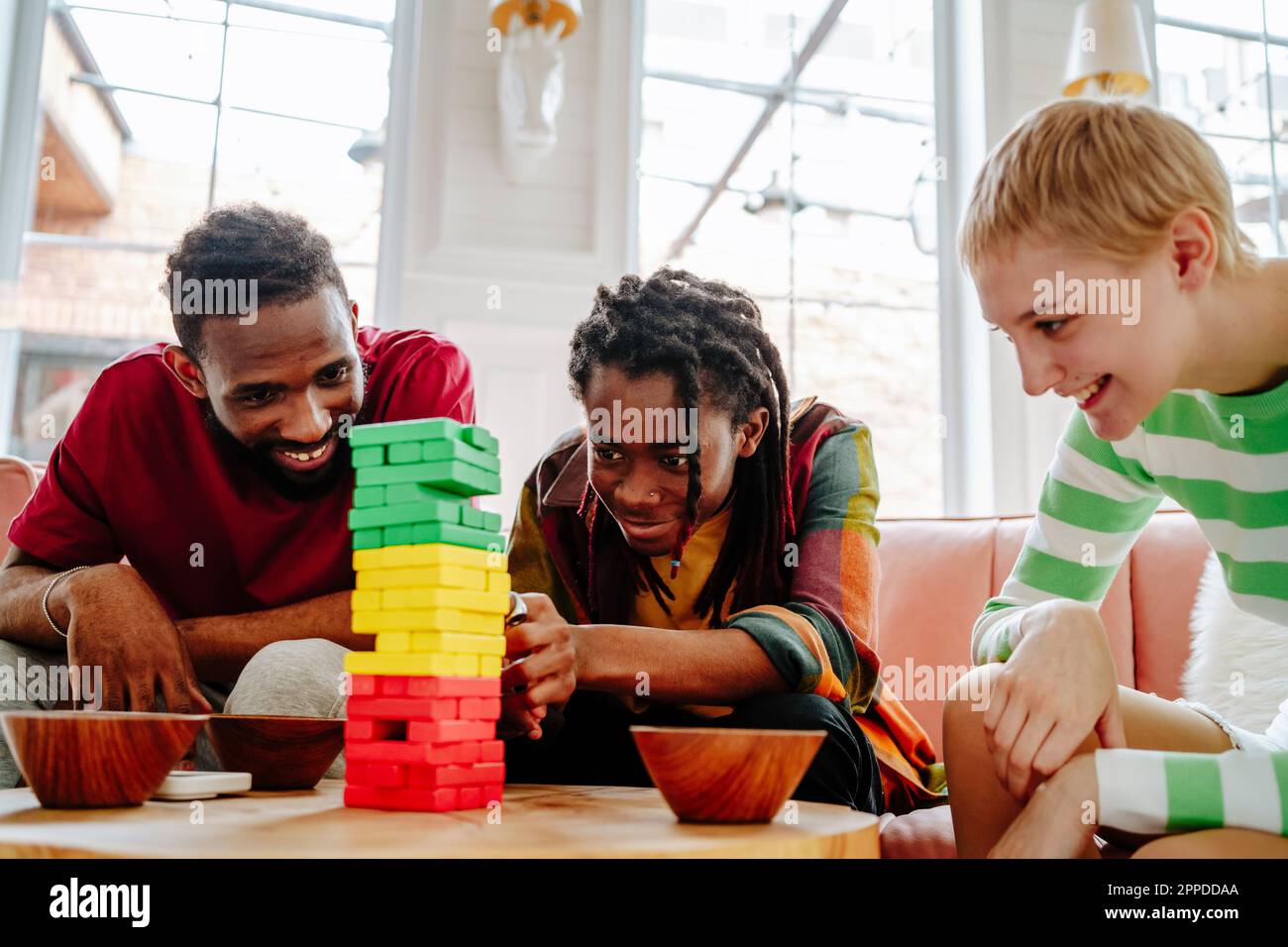 Happy young man playing block removal game with friends Stock Photo - Alamy