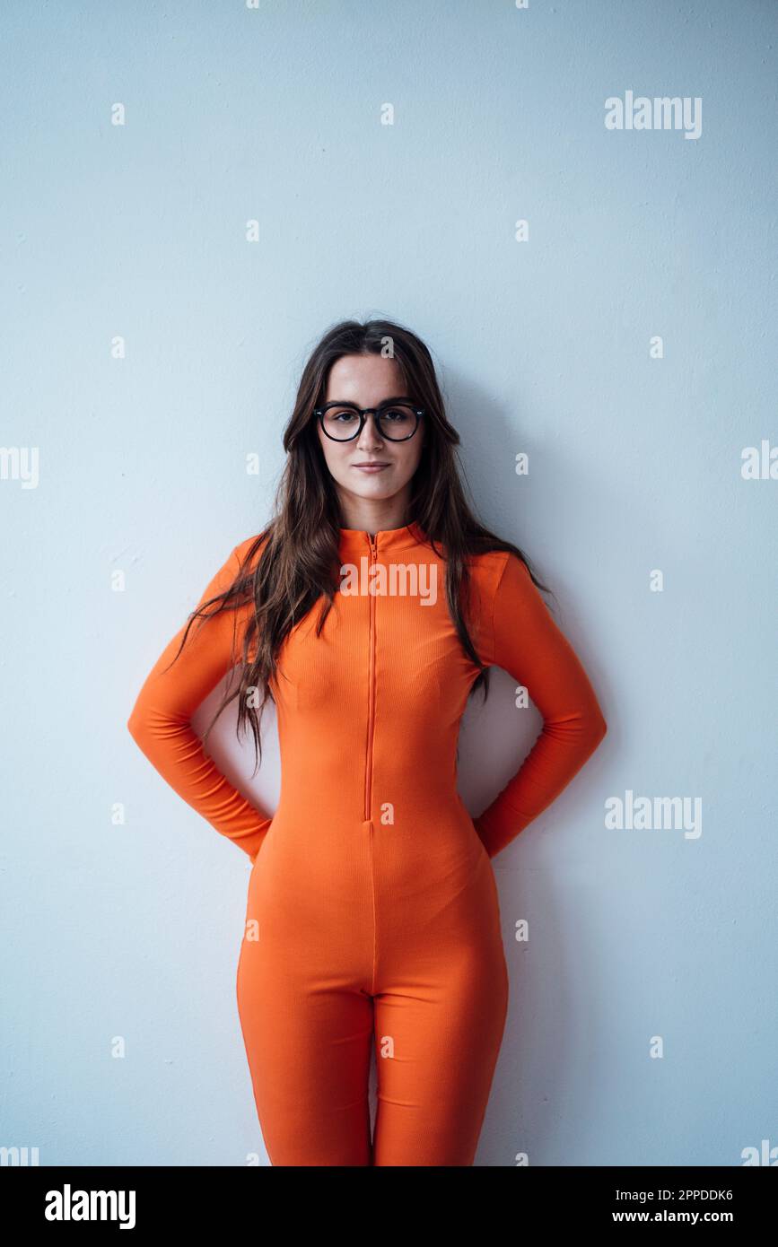 Woman wearing orange jumpsuit leaning on wall Stock Photo - Alamy