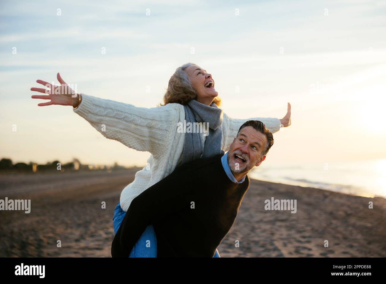 Cheerful mature woman enjoying piggyback ride at beach Stock Photo - Alamy