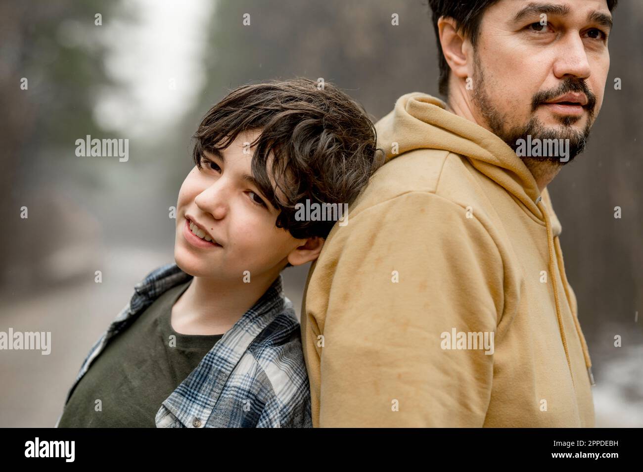 Thoughtful teenage boy leaning on father's back Stock Photo - Alamy