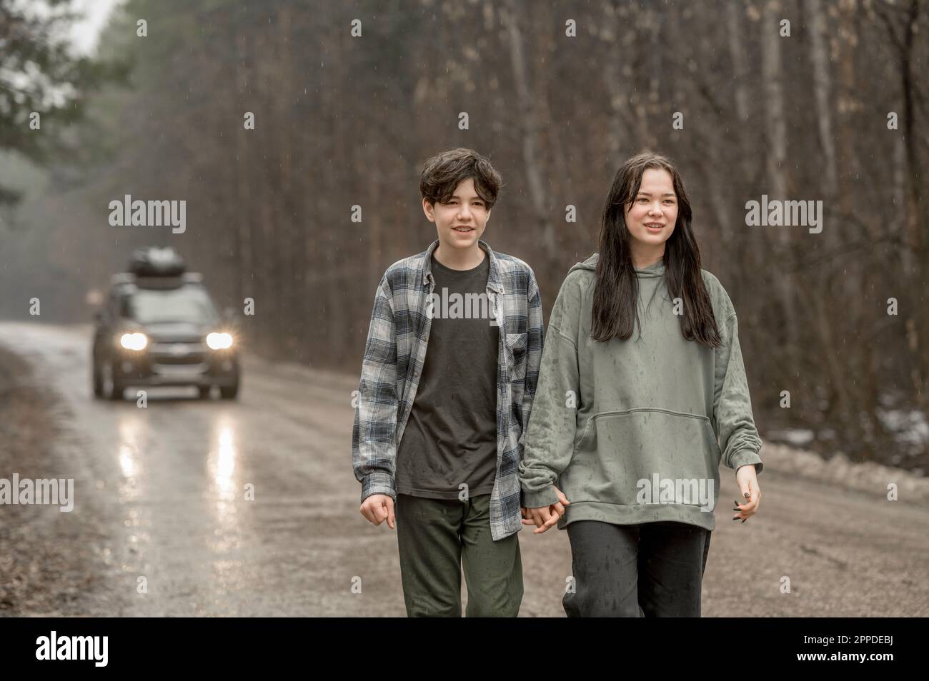 Brother and sister holding hands and walking on wet road Stock Photo ...