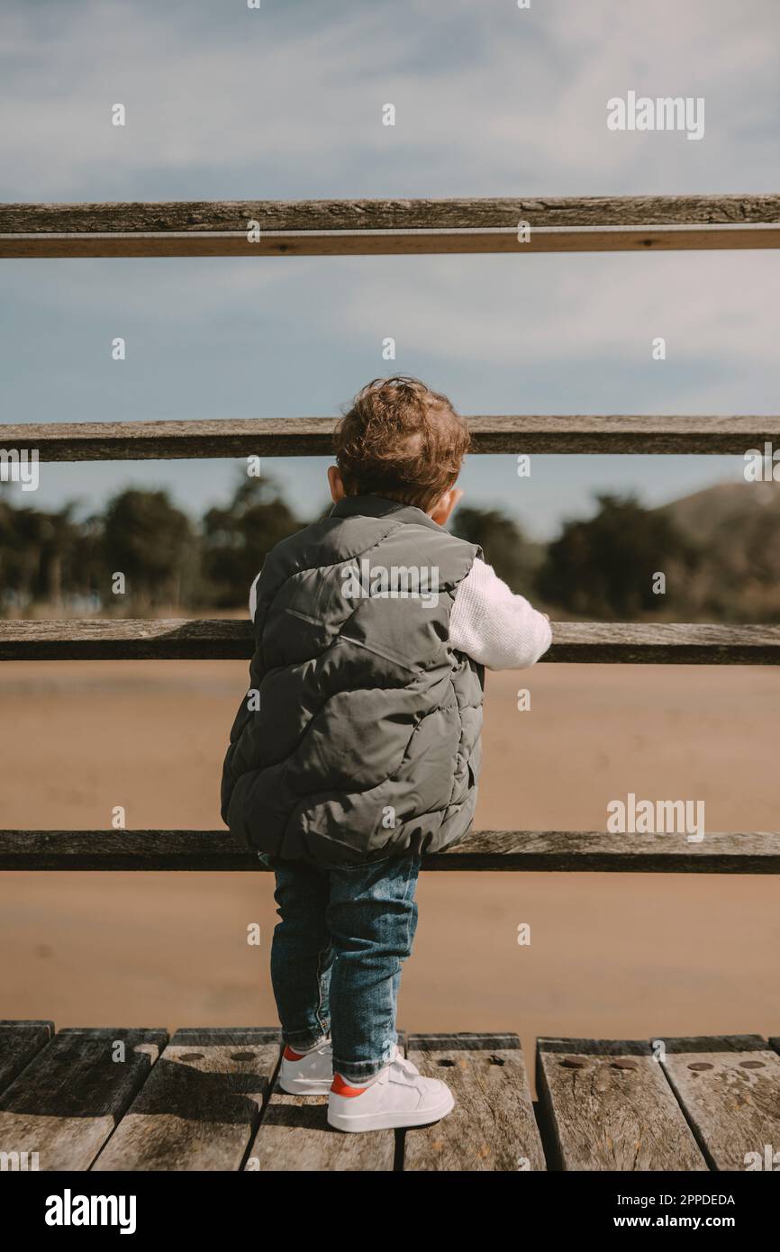 Boy standing by railing looking at view Stock Photo - Alamy