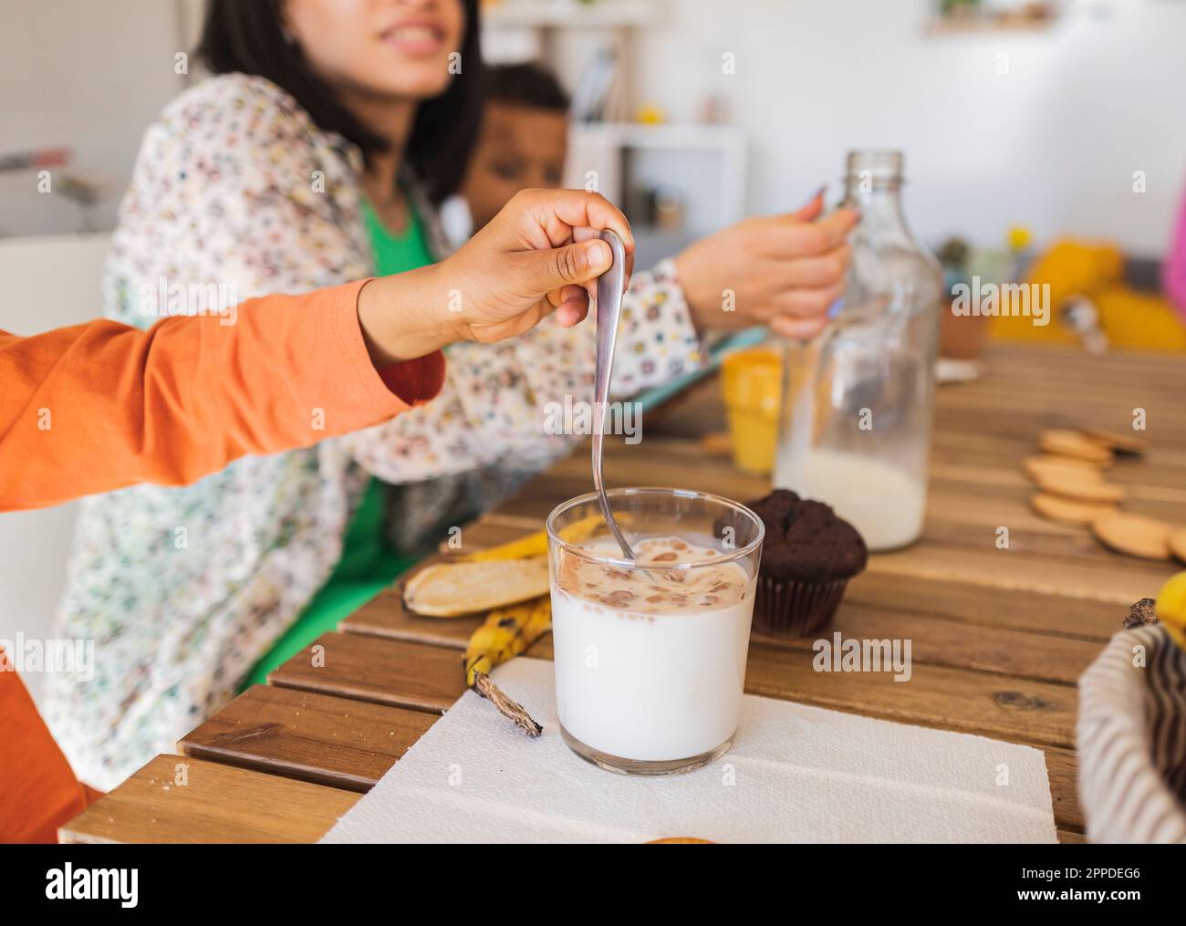 Boy stirring milk with spoon by mother at home Stock Photo - Alamy