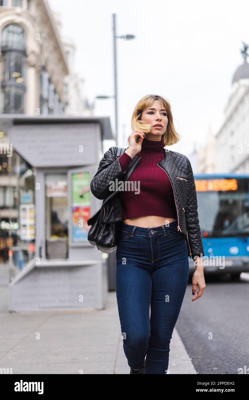 Woman wearing leather jacket walking on sidewalk Stock Photo - Alamy