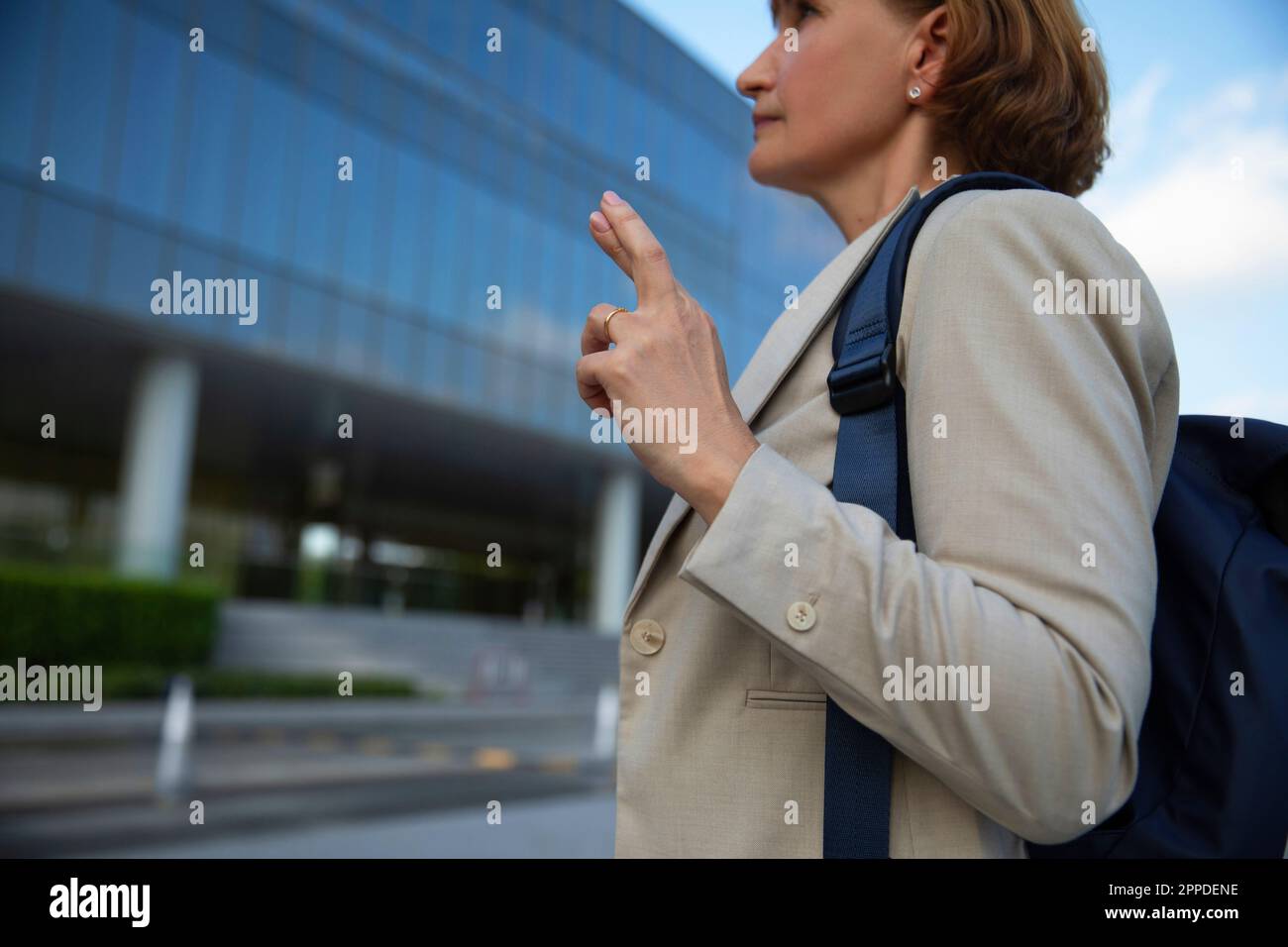 Businesswoman wearing backpack standing with crossed fingers Stock ...