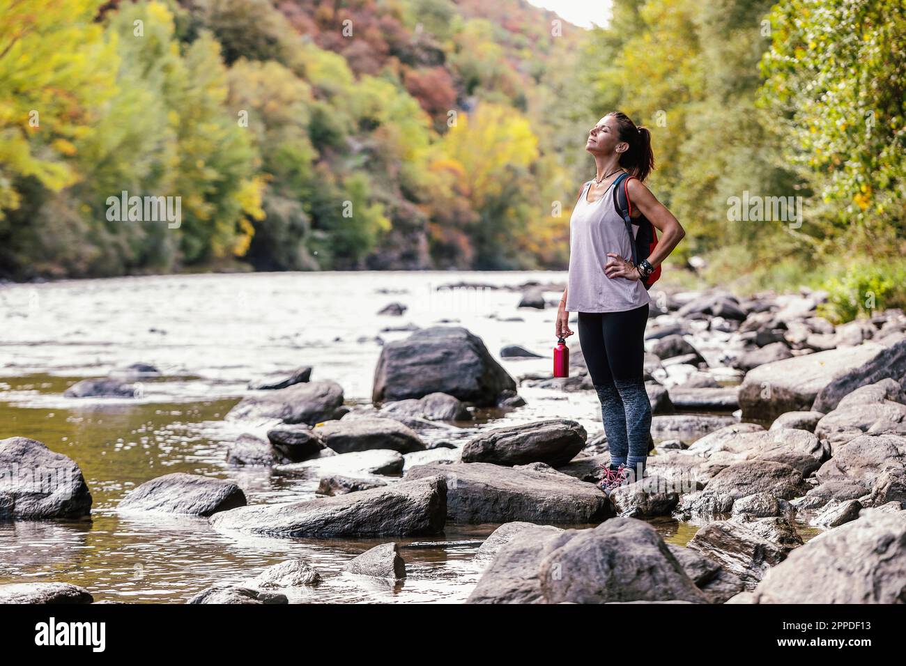Woman with hand on hip enjoying nature near river Stock Photo - Alamy