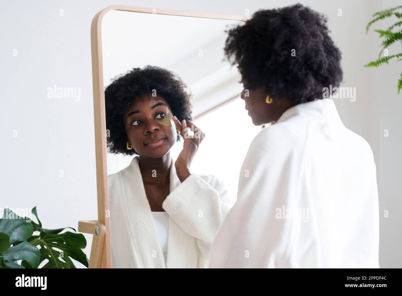 Woman applying eye patch looking in mirror Stock Photo - Alamy
